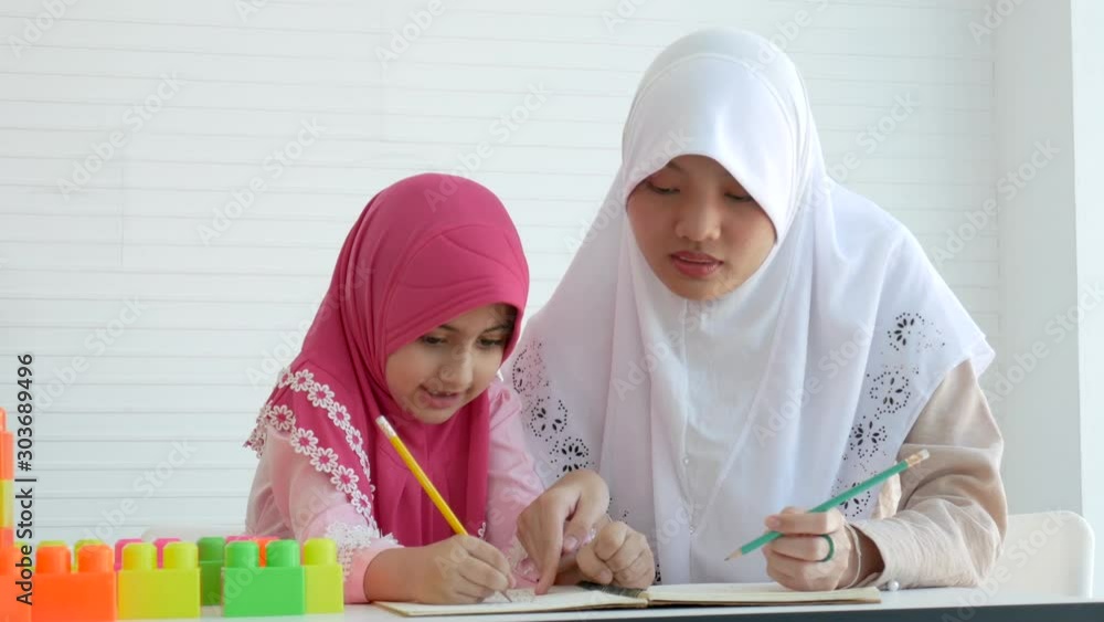 Muslim child with pink hijab learn something with her teacher on white ...
