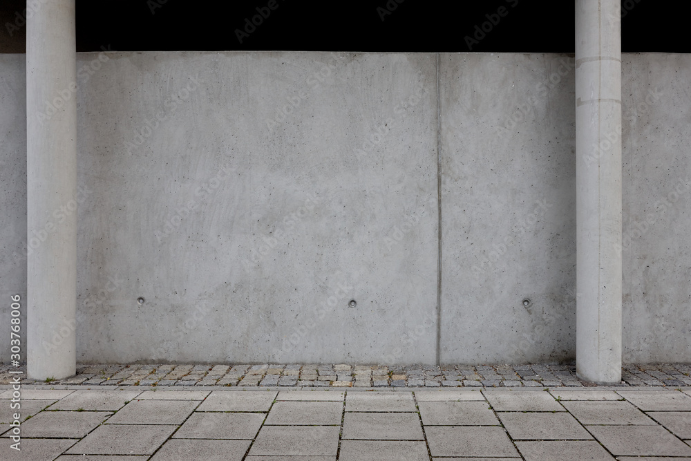 Graue Betonwand mit Säulen und gepflastertem Bürgersteig Stock Photo ...