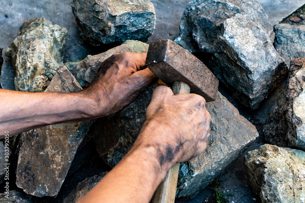 The dirty hands of a slave hold a hammer among the stones. Slave hard ...