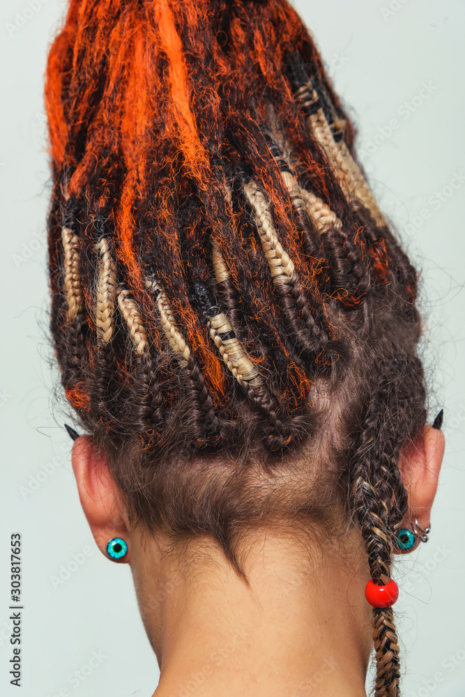 Girl with red fire dreadlocks gathered in a tail on a white background ...