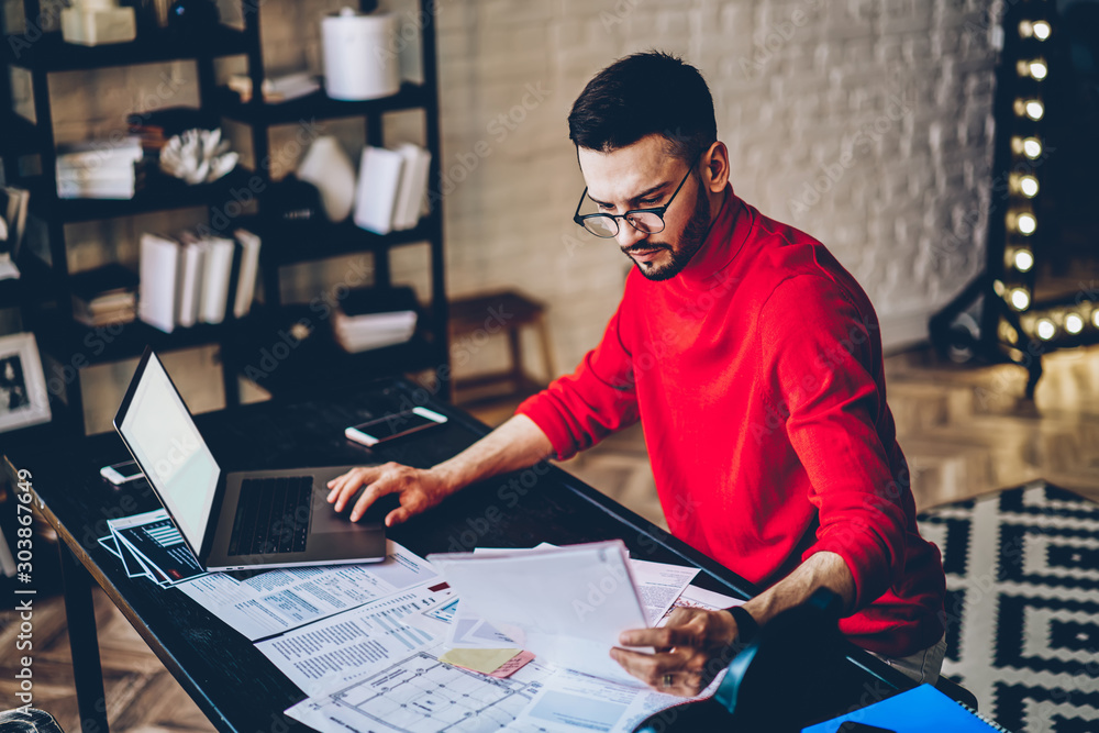 Concentrated businessman working remotely at desktop in home interior ...