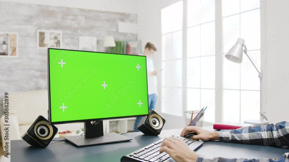 Zoom out footage of male typing on keyboard of a green screen PC ...