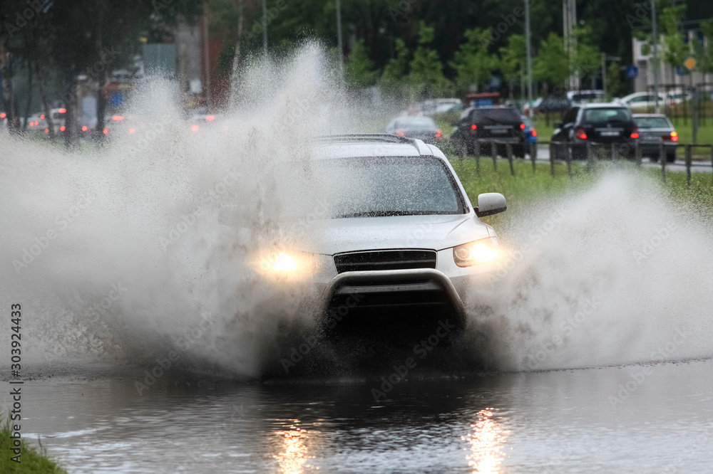 Driving car on flooded road during flood caused by torrential rains ...