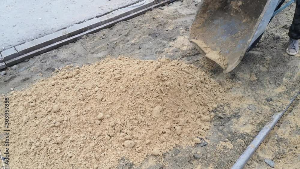 A man transported sand in a wheelbarrow, turned a wheelbarrow and pour ...