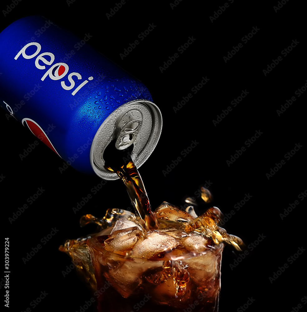 POLTAVA, UKRAINE - MARCH 22, 2018: Splash pepsi into a glass on a black ...