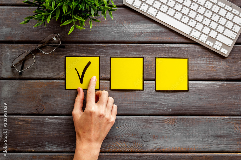 Hand put check mark in yellow check-box on dark wooden office ...