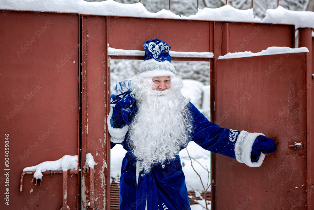 Father Frost enters the gate. Winter day. Santa Claus carries a bag of ...