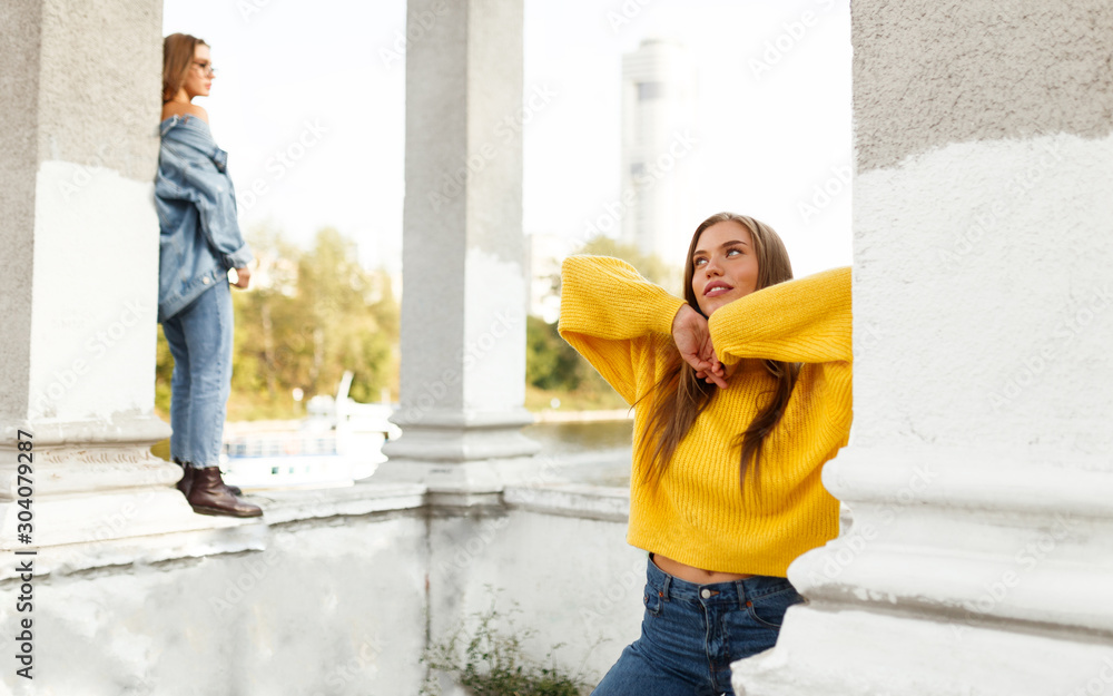 Horizontal view. Two attractive girls sits beside white columns. Sexy ...