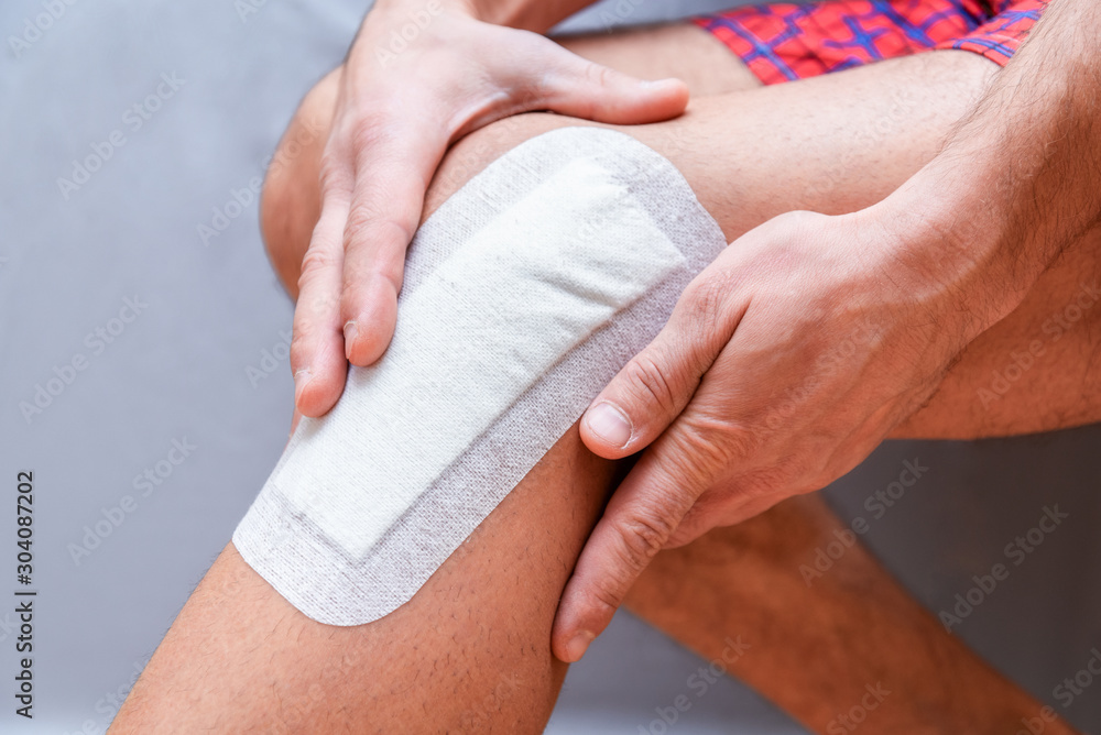 Poster medical plaster is glued to the knee of the male leg after ...