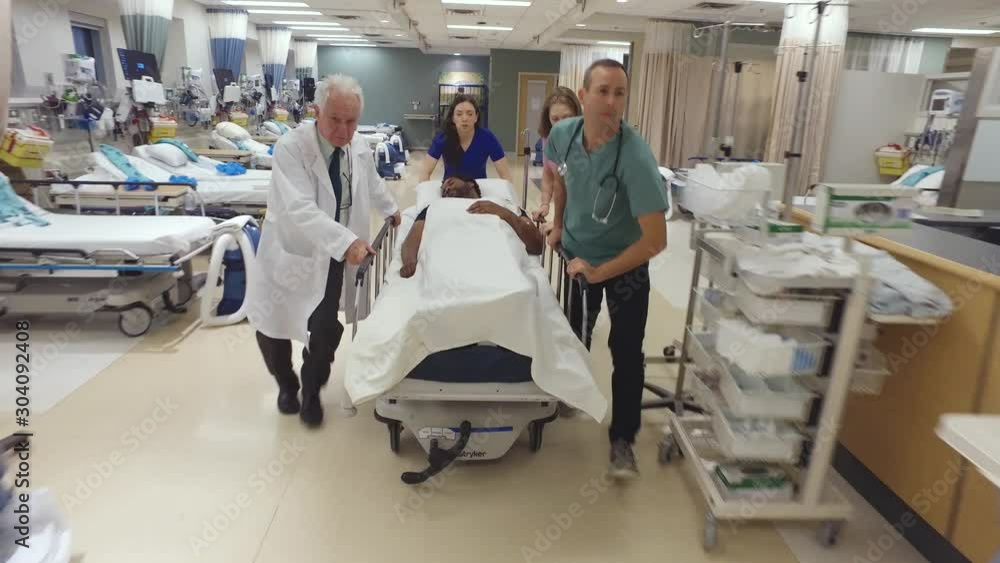 A sick patient being rushed on a gurney by a doctor and nurses through ...