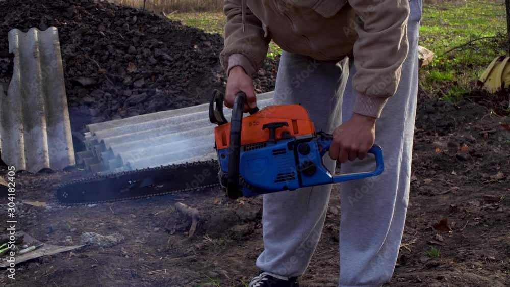The man starts a chainsaw, a chainsaw with a two-stroke engine. The ...