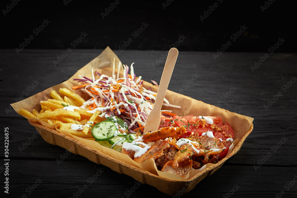 Cardboard box filled with barbecue food: kebab, vegetables, french ...