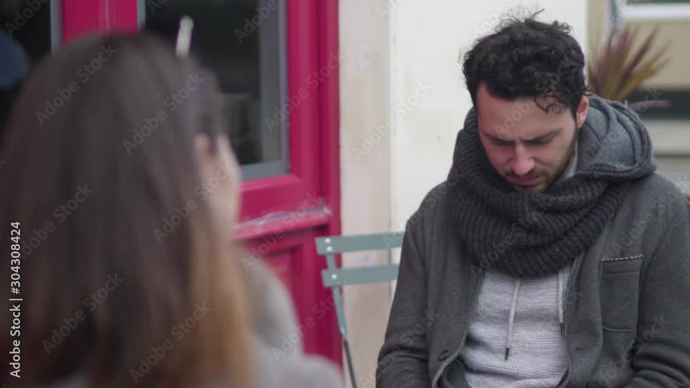 A depressed and unhappy man sitting across to his girlfriend with a sad ...