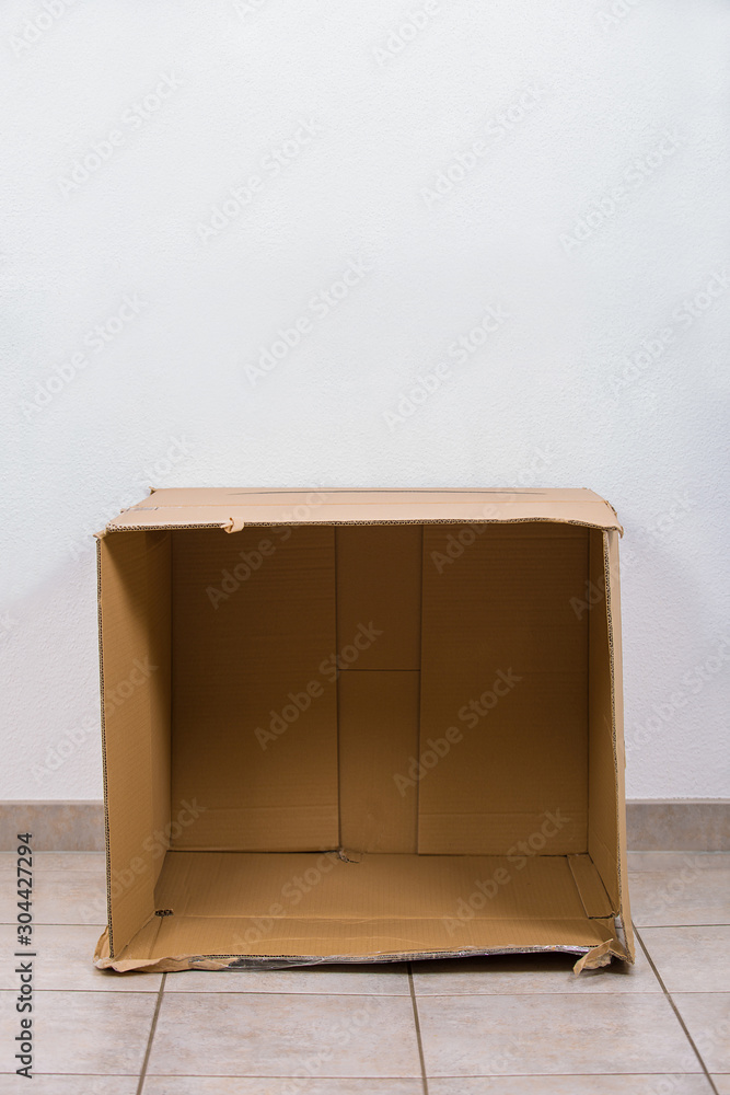 Open empty cardboard box on the floor inside a room with copy space on ...