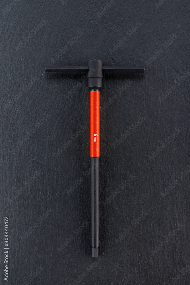Professional reinforced black matt T-shape wrench placed on a dark ...