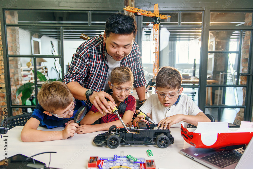 Male electronic engineer with european school children working in smart ...
