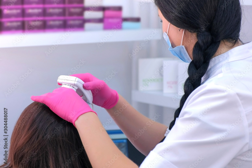 Trichologist examines woman patient's hairs using computer trichoscopy ...