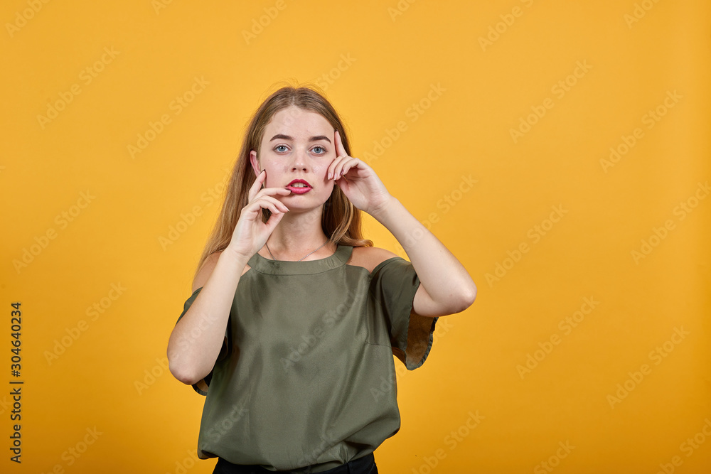 Young beautiful caucasian woman keeping hand on face, model gesture ...