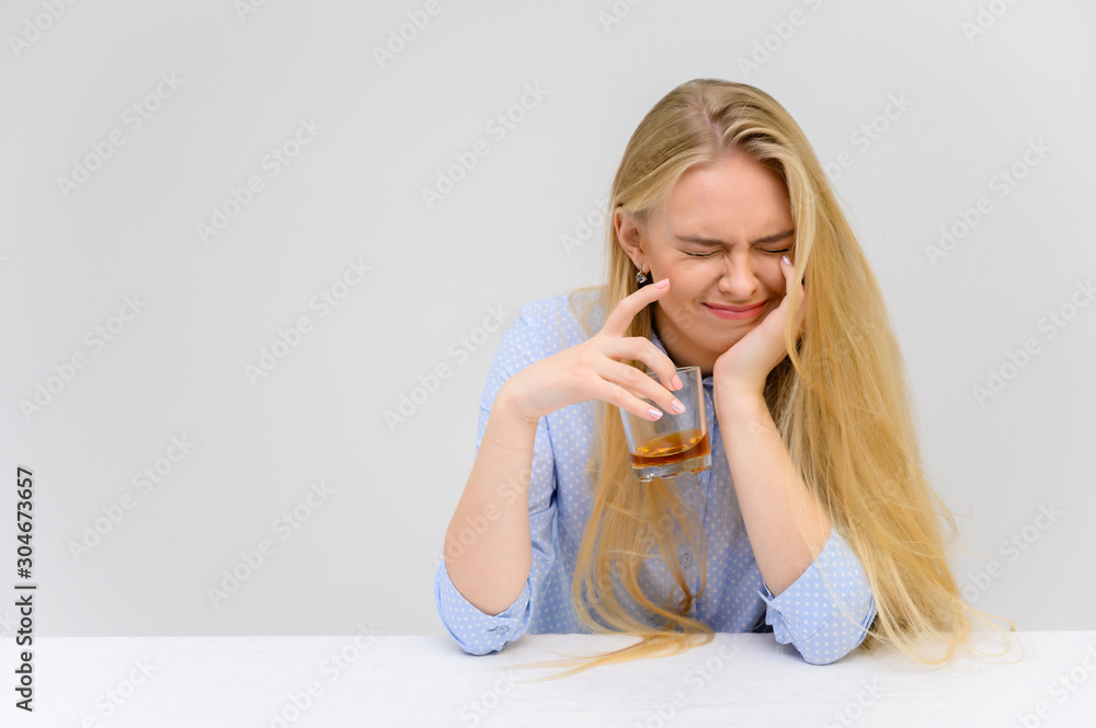 Concept woman with alcohol problems sits at a table with whiskey in a ...