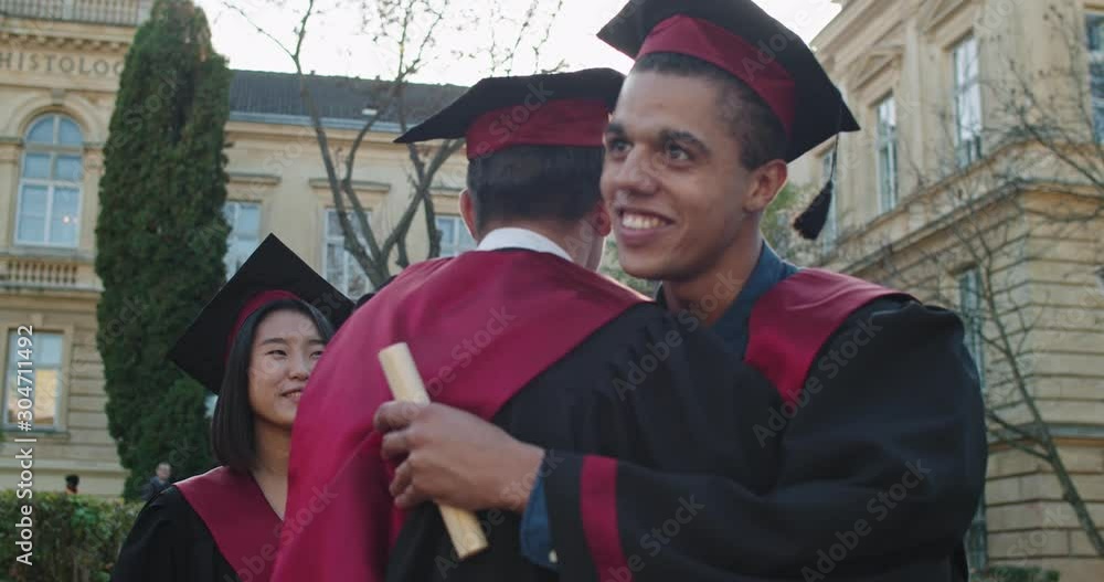 Two multiethnic young guys friends, graduated students in academic ...