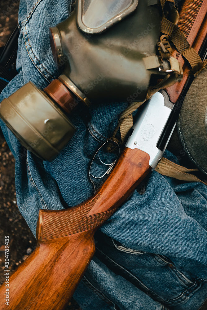 Fotka „A double barrel shotgun and a gas mask on a denim jacket. Still ...
