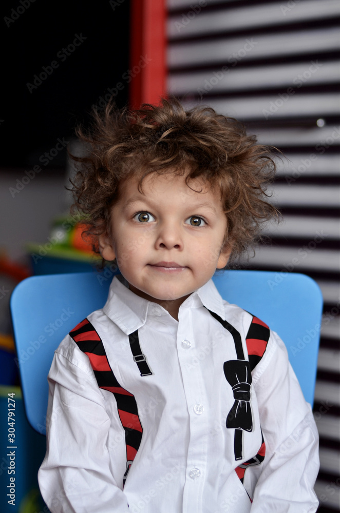 curly-haired handsome charismatic boy in a beautiful shirt in his room ...