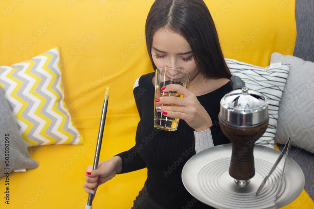 Recreation and entertainment. Young beautiful girl smokes a hookah in a ...