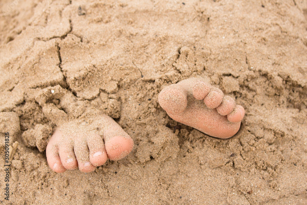 Feet buried in sand on the coast of Scotland on a sunny day. Stock ...