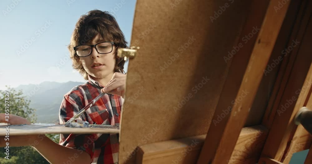 Young kid drawing a picture in mountains. Little boy making first steps ...