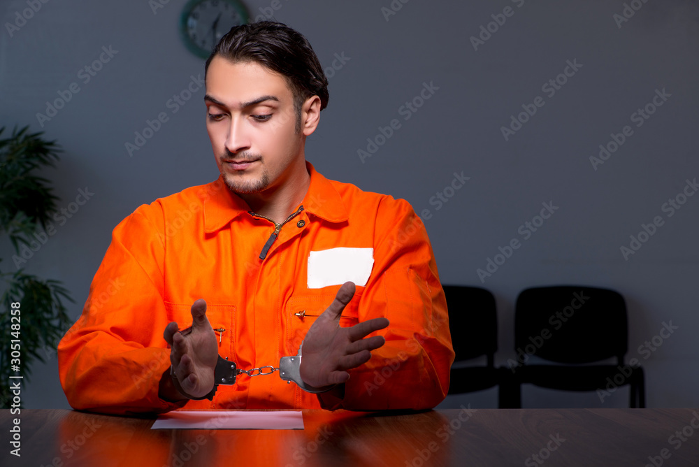 Young convict man sitting in dark room Stock Photo | Adobe Stock