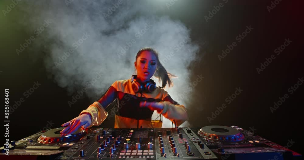 Asian female disc jockey working at controller, professional dj doing a ...