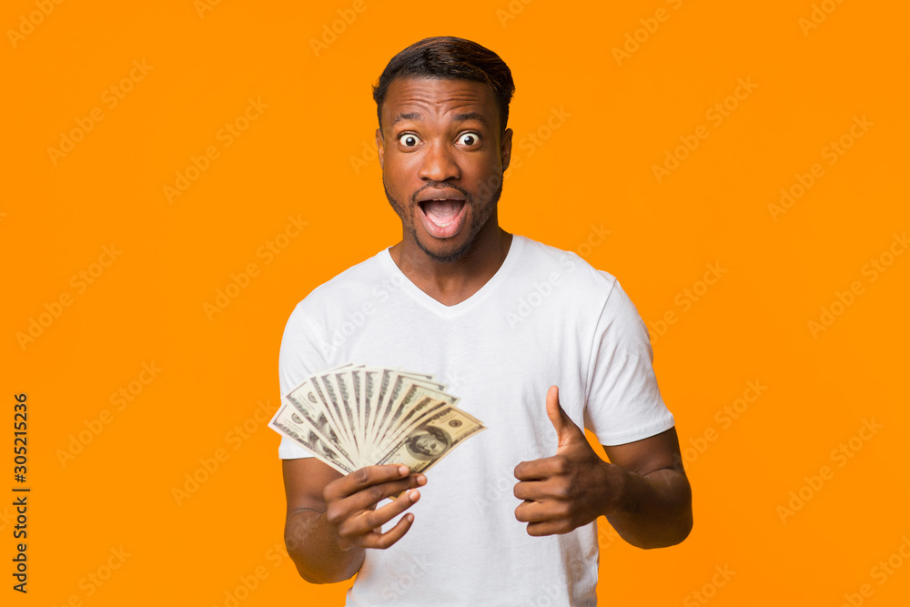 Surprised Black Man Holding Money Gesturing Thumbs-Up Standing, Studio ...