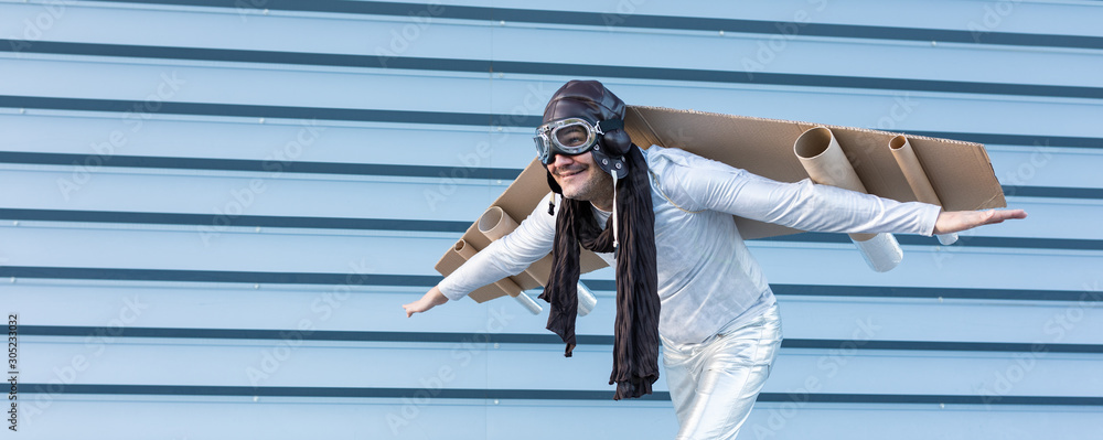 man in silver suit with glasses and aviator helmet and cardboard plane ...
