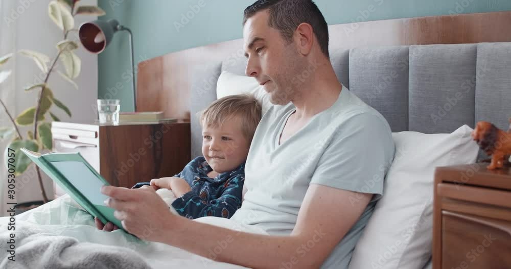 Dad reading a book in bed to young boy, bedtime stories daily routine ...
