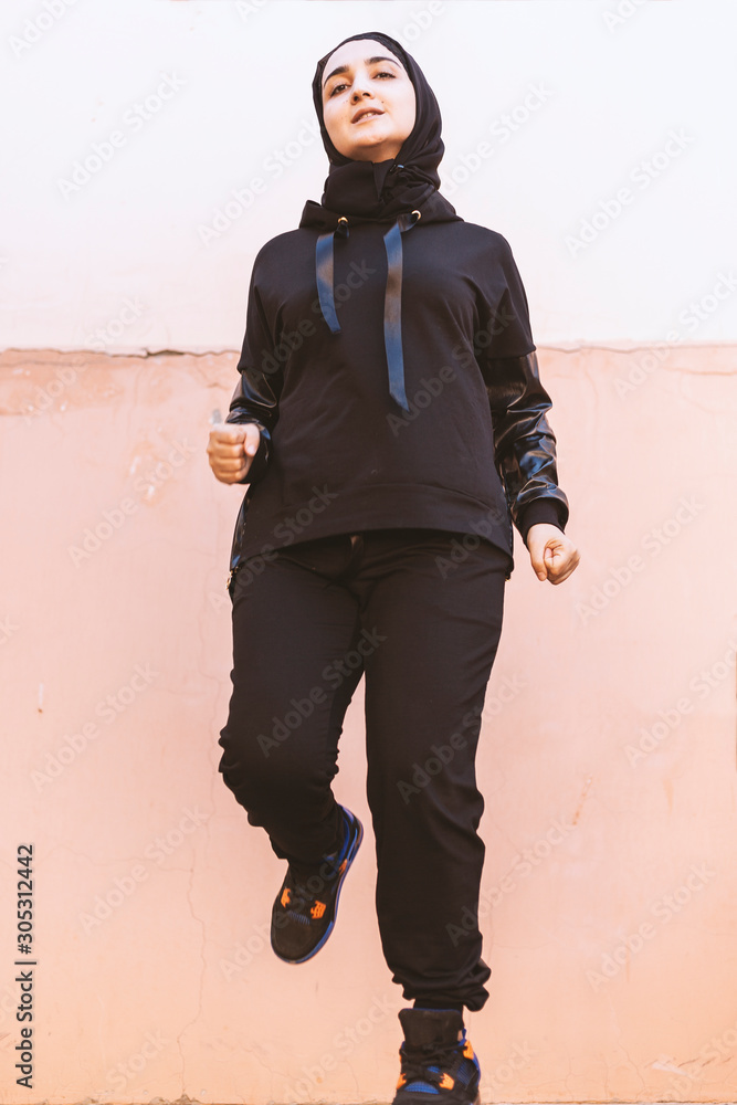 Muslim woman running. Middle-eastern woman in hijab training outdoors ...