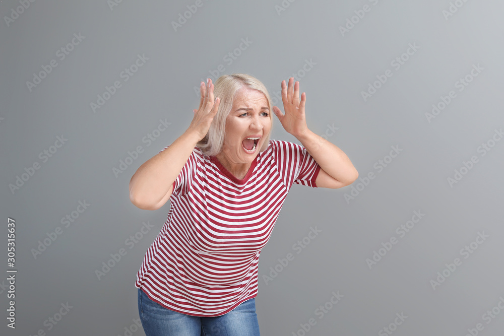 Angry mature woman on grey background Stock Photo | Adobe Stock