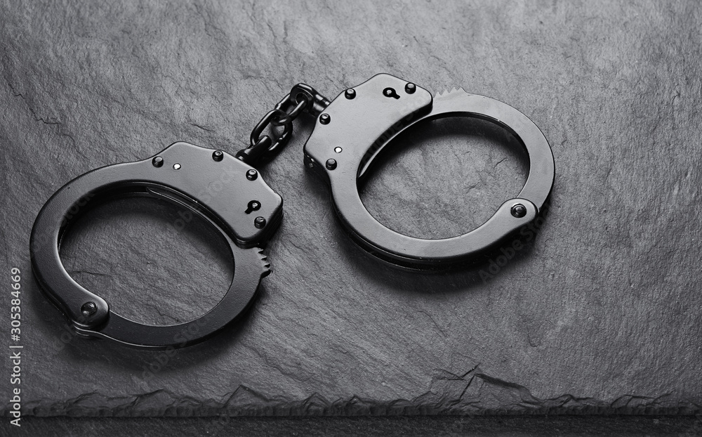 Old black handcuffs on stone background Stock Photo | Adobe Stock