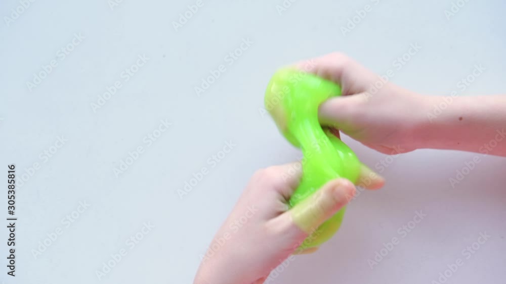 Girl stretching green slime to the sides. kids hands playing slime toy ...