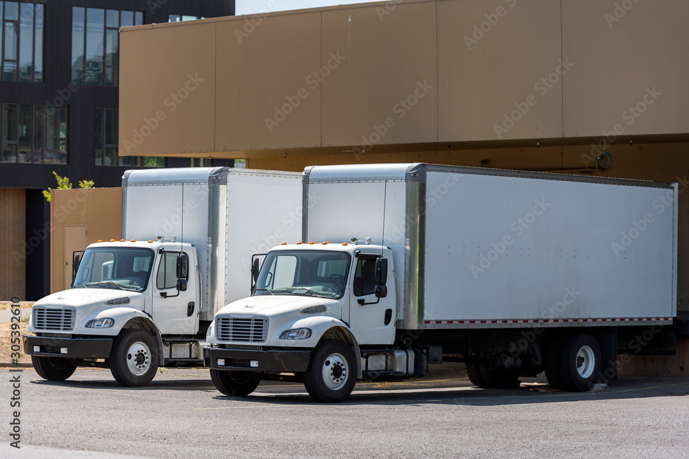 Small compact rigs semi trucks with long box trailers standing in ...