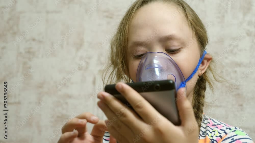child with a tablet is sick and breathes through an inhaler. close-up ...