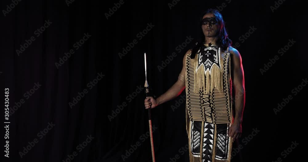 Muscular native american man with a spear is standing in red and blue ...