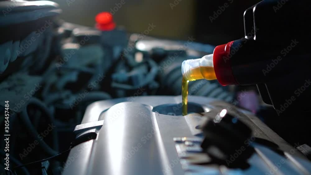 Engine oil change. Fresh engine oil pouring from the canister into the ...