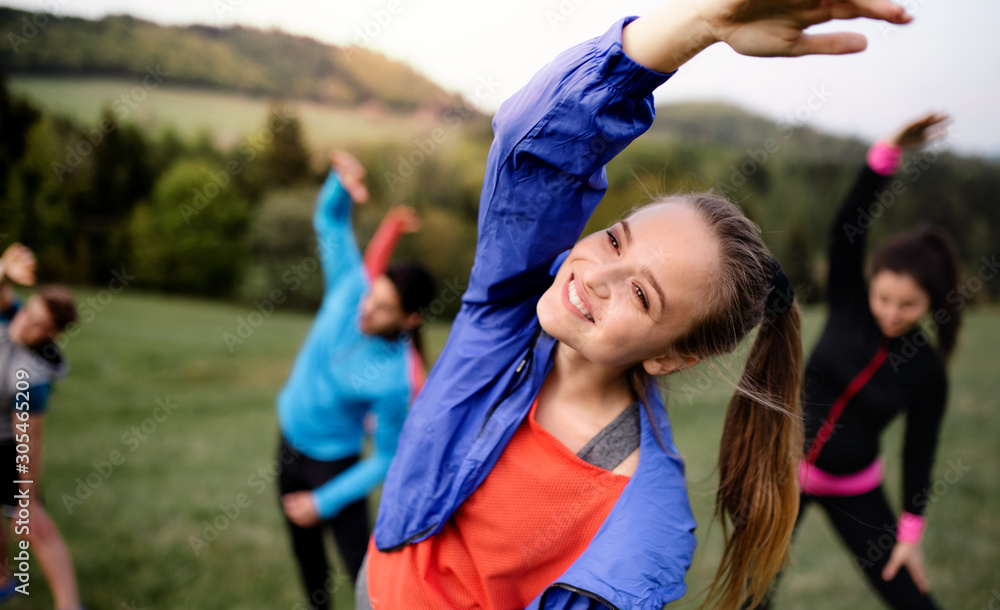 Large group of fit and active people doing exercise in nature ...