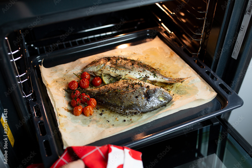 Cooking fish in the oven. Cooking dorado with cherry tomatoes and herbs ...