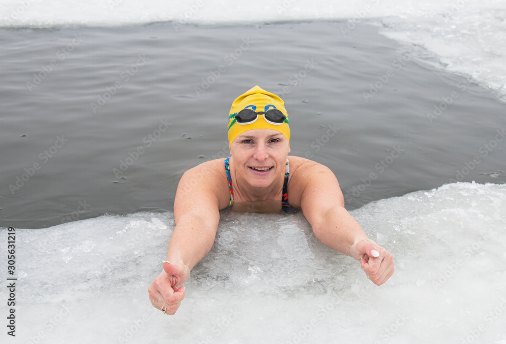 woman in the ice hole in winter in a swimsuit, winter extreme swimming ...