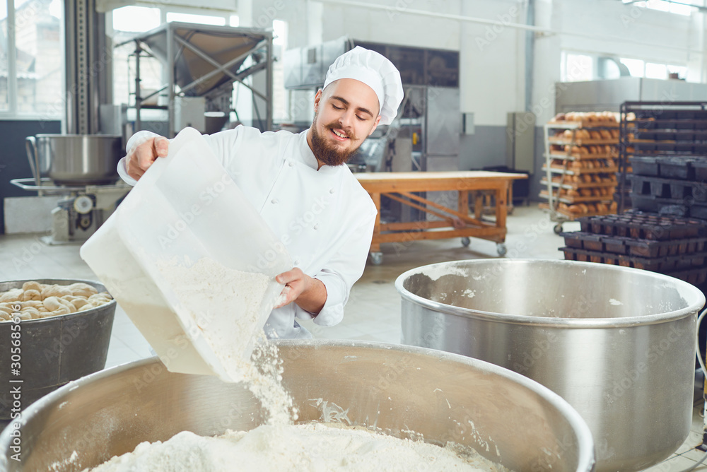 Smiling man adding flour in big steel container Stock Photo | Adobe Stock
