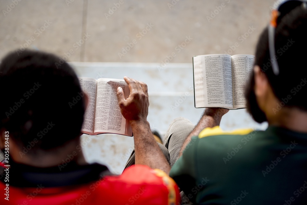 Overhead shot of people sitting and reading the bible with a blurred ...
