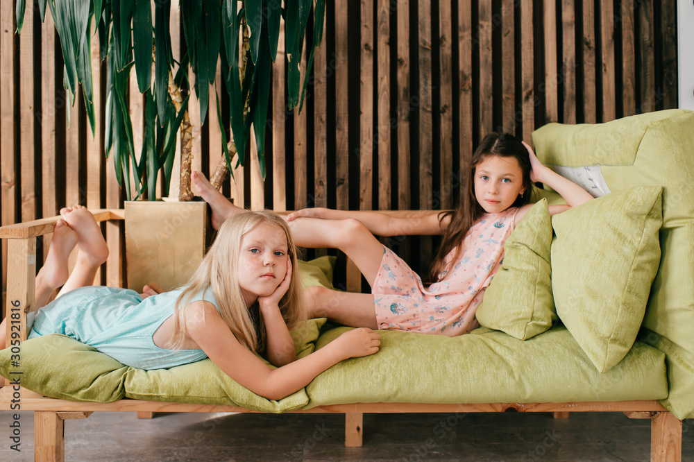 Two beautiful model girls lying on bed in interior studio and posing ...