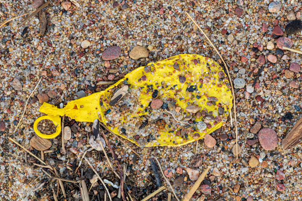 Environmental pollution - a worn yellow balloon, lying on the beach as ...
