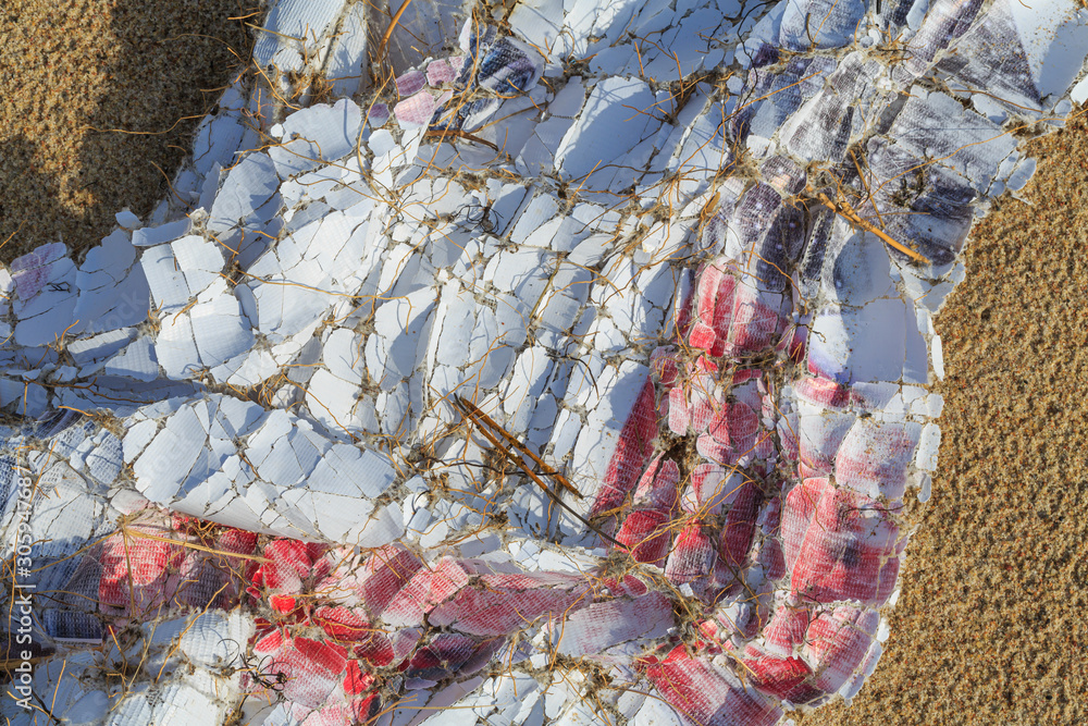 Environmental pollution - a worn tarpaulin, lying on the beach as waste ...